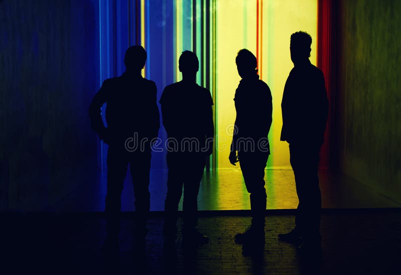 Silhouette of Four People Standing on Highlighted Wall Background Stock ...