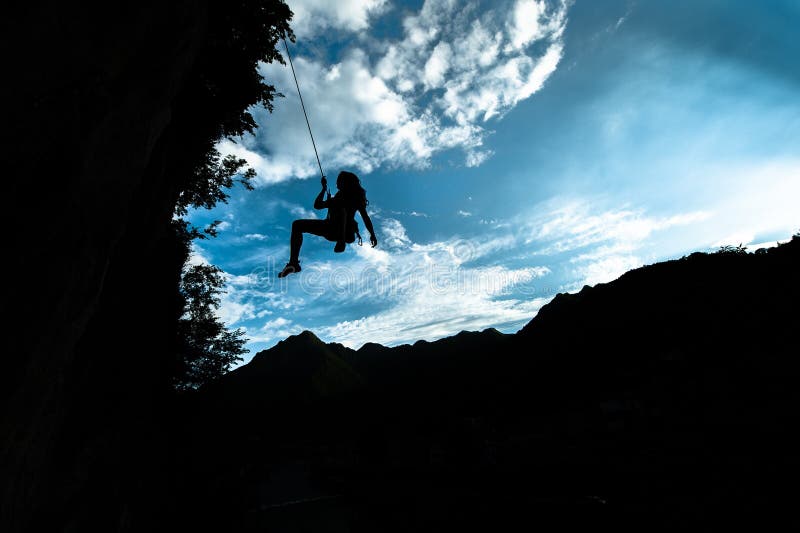 Silhouette of a Rock Climber Descending on the Rope after Climbing at ...