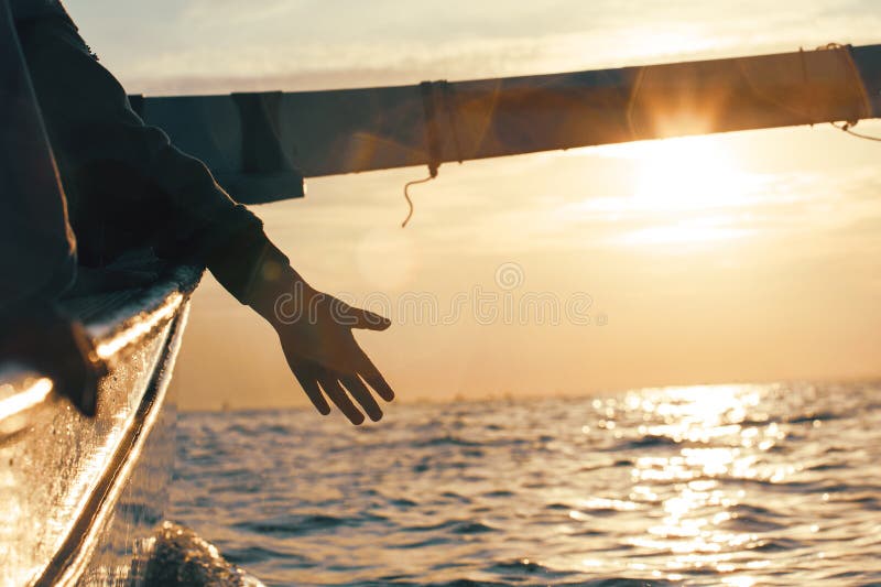 Silhouette of a Hand from a Boat on a Sunset Background Stock Image ...