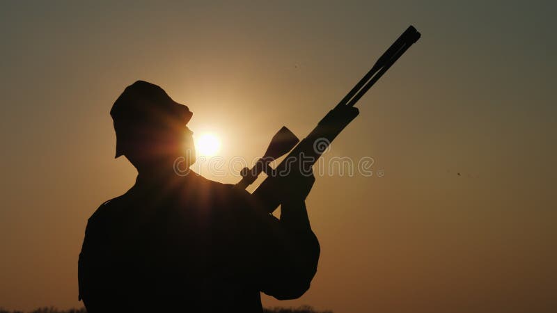 Silhouette of a Hunter with a Gun, the Sun`s Rays Shine in His Face ...