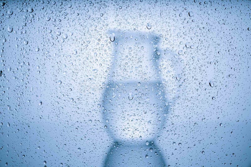 Silhouette of a Jug of Water Behind Glass Covered with Water Drops ...