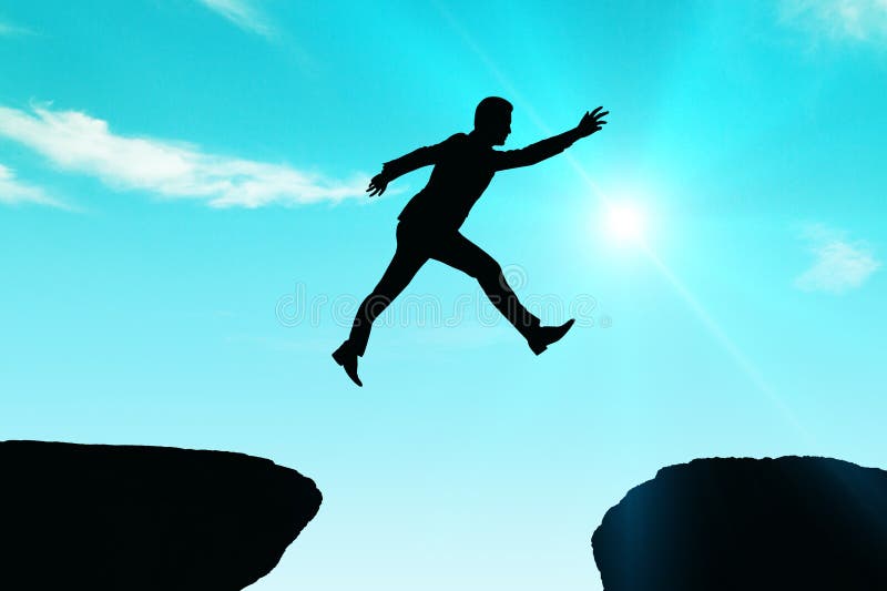 Silhouette of a Man Jumping between Cliffs Against a Bright Sky Stock ...