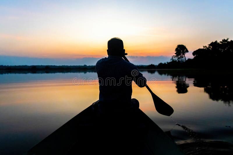 Silhouette of a Man Paddling Canoe at Dusk Calm Water Stock Photo ...