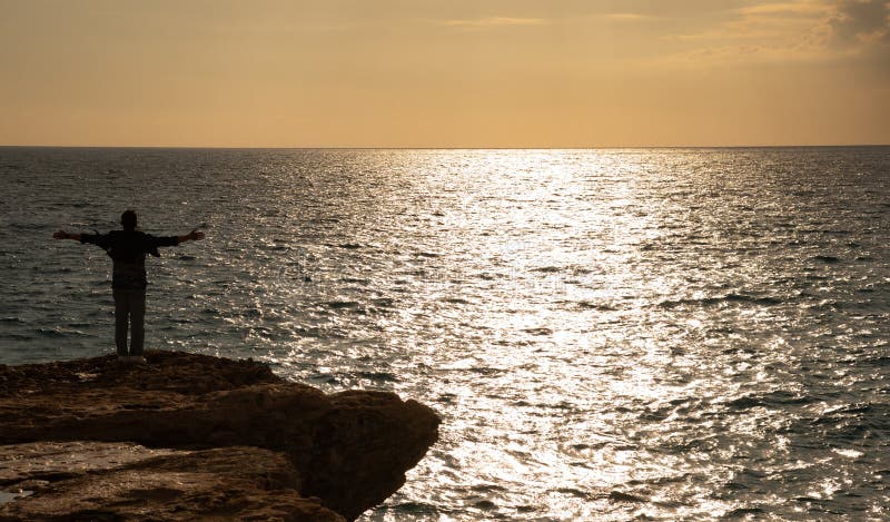 Silhouette of Man Raising Hands or Open Arms at Sunset at the Edge of ...