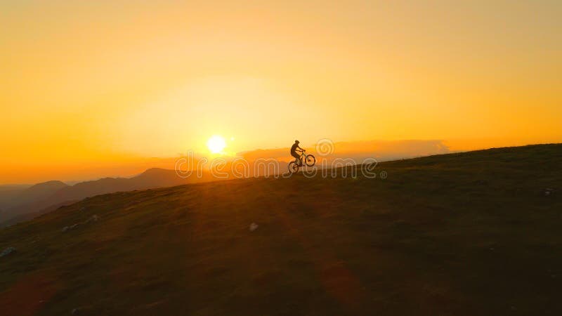 SILHOUETTE: Man Riding a Mountain Bike Does a Wheelie while Riding ... SILHOUETTE: Man Riding a Mountain Bike Does a Wheelie while Riding ...