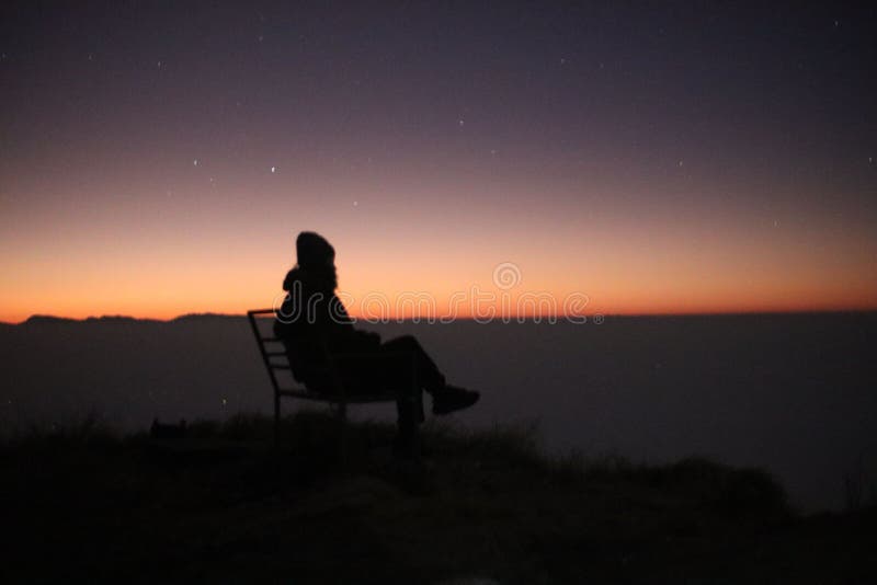 Silhouette of a Man Sitting on Top of a Hill, Enjoying the View of ...