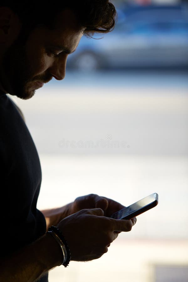Silhouette of Man Texting on Mobile Phone Standing by Window Stock ...