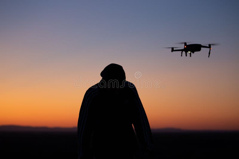 Silhouette of a Person Flying a Drone in a Sunset Sky Stock Photo ...