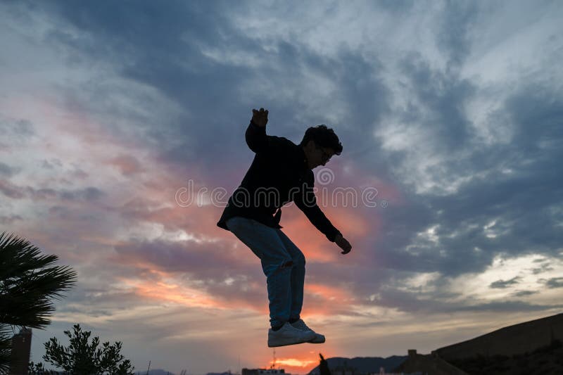 Silhouette of a Person Jumping Outdoors with the Sunset Sky on ...