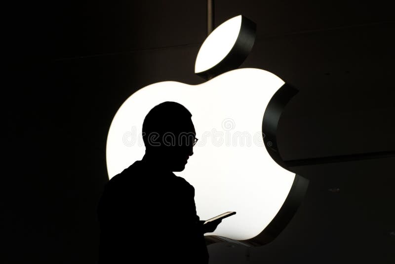 Silhouette of a Person Using Mobile Phone in Front of the Apple Logo ...