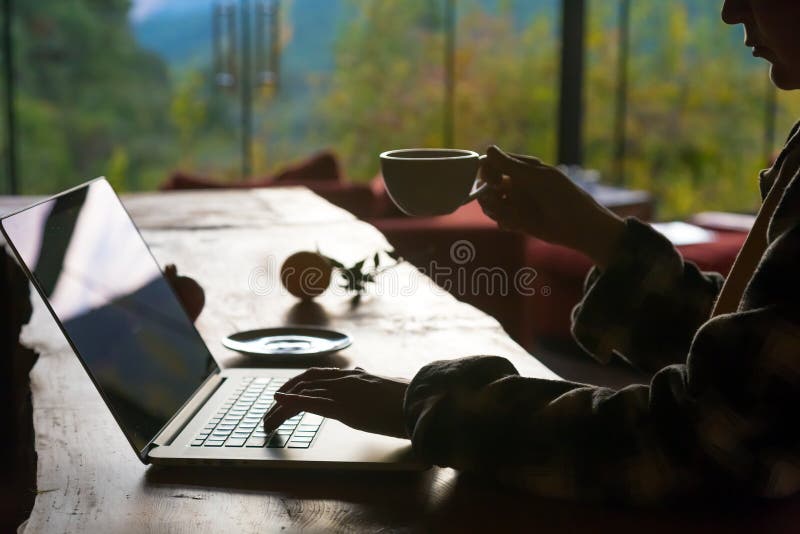 Silhouette of Person Working on Computer Drinking Coffee at Wooden ...