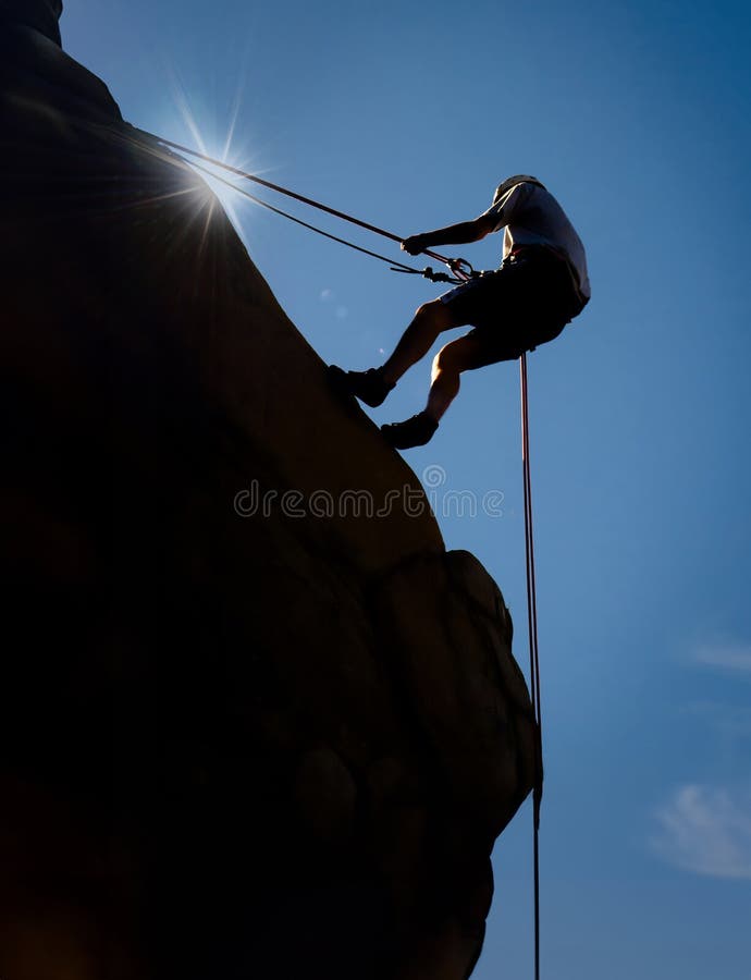 Silhouette of a Rock Climber Repelling on a Steep Rock Boulder Against ...