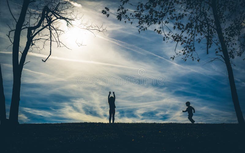 Silhouette Shadows of Two Children on a Hill with a Blue Sky Behind ...