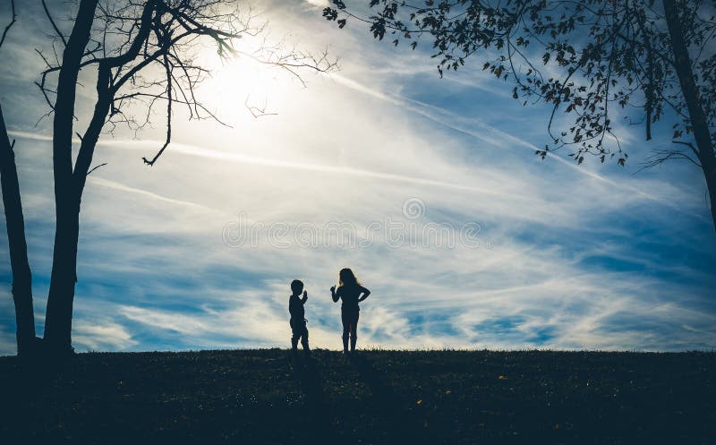 Silhouette Shadows Of Two Children On A Hill With A Blue Sky Behind ...