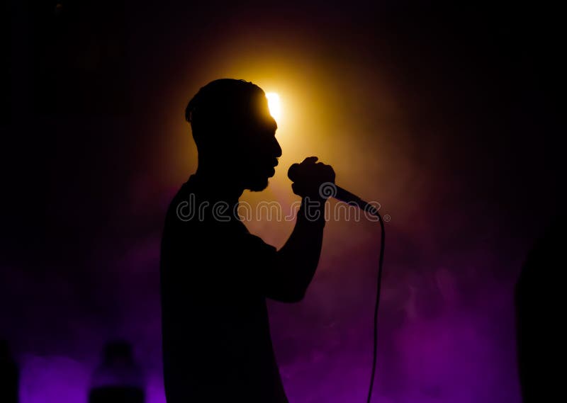 Silhouette Shot of a Man Singing Using a Microphone Inside a Club with ...