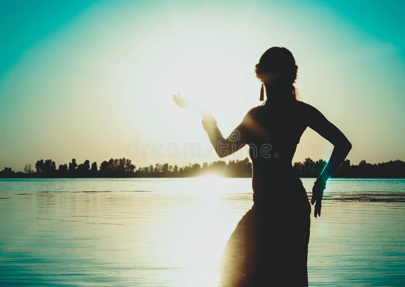 Silhouette Of Slim Woman With Hands Up In The Air Illuminated With