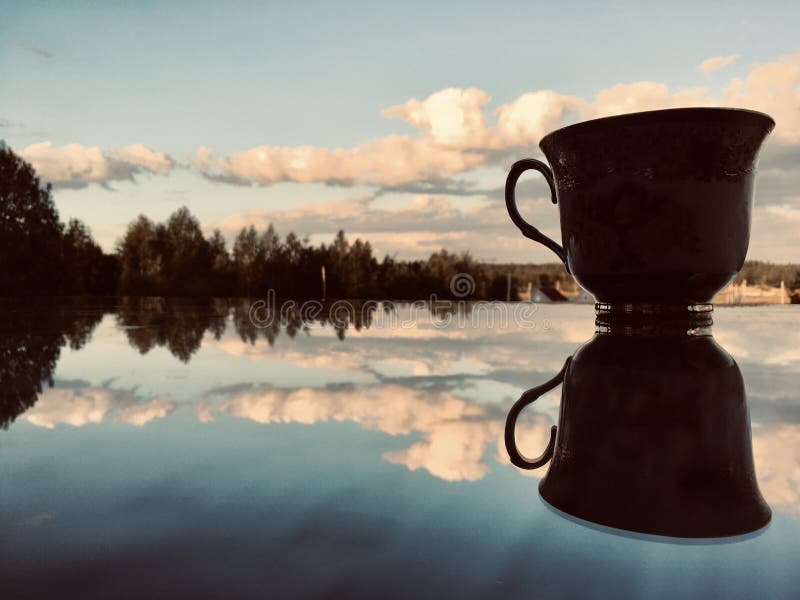 Silhouette of a Tea Cup is Reflected in the Mirror Surface of the Glass ...