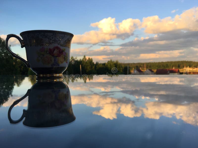 Silhouette of a Tea Cup is Reflected in the Mirror Surface of the Glass ...