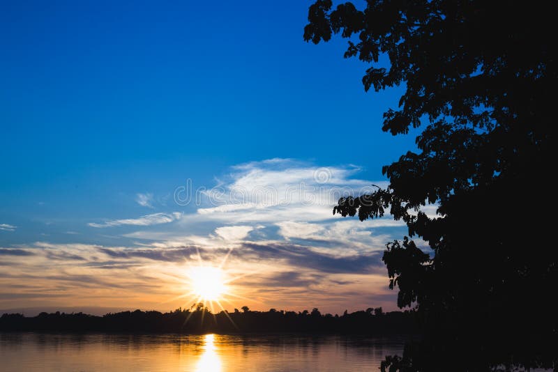 Silhouette of Tree on Right with River and Sun Flare on Sunset Stock ...