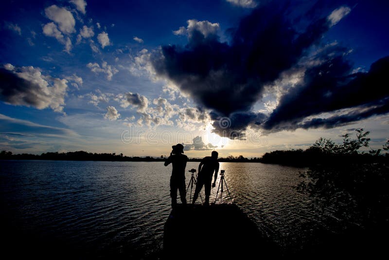 Silhouette of Two Man on the River Under the Sunset Stock Image - Image ...
