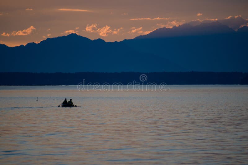 Silhouette of Two Men Rowing in a Boat with Mountains in Distance Stock ...