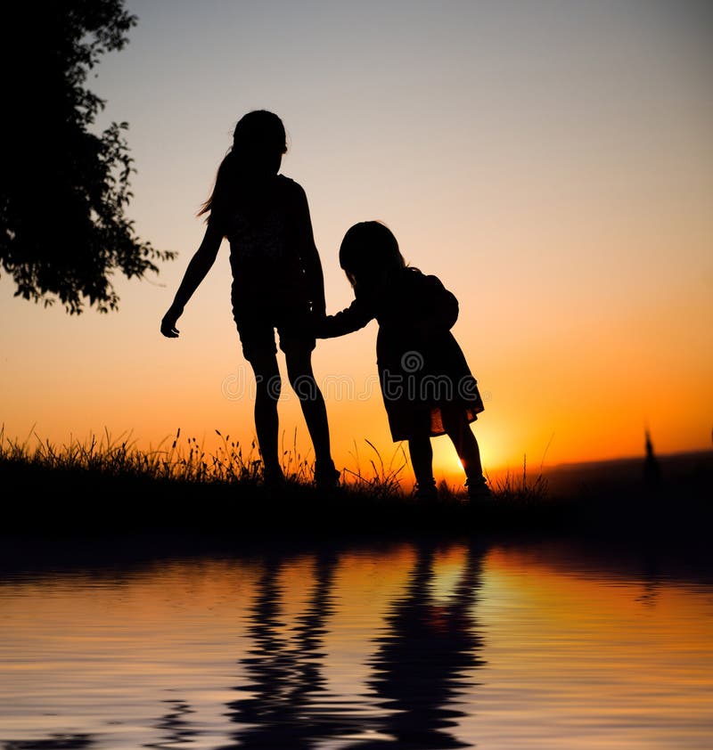 Silhouette of Two Sisters Holding Hands Who Standing on the Beach at ...