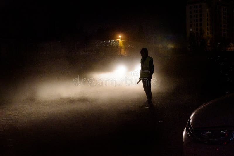Silhouette of Unrecognizable Man Illuminated by the Headlights of a Car ...