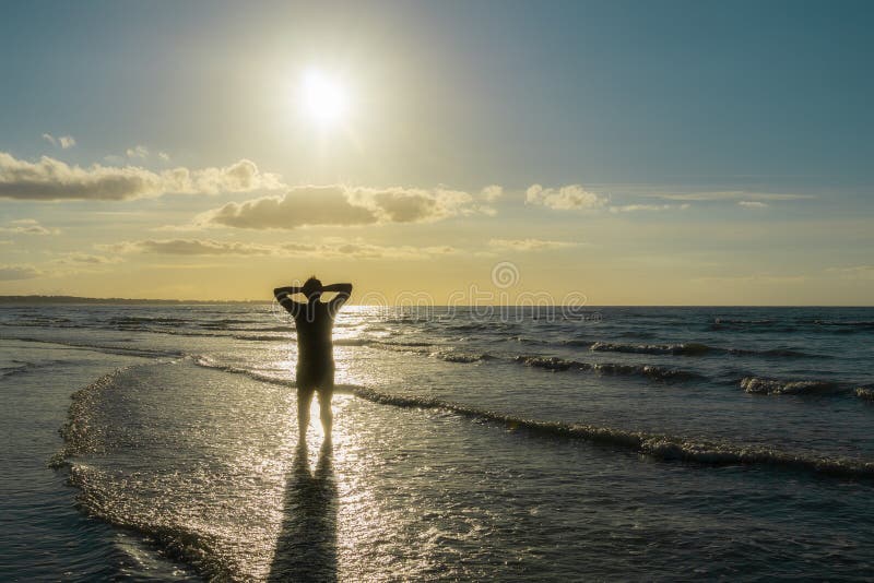 Silhouette of a Young Man Standing on the Seashore Facing the Sun Stock ...