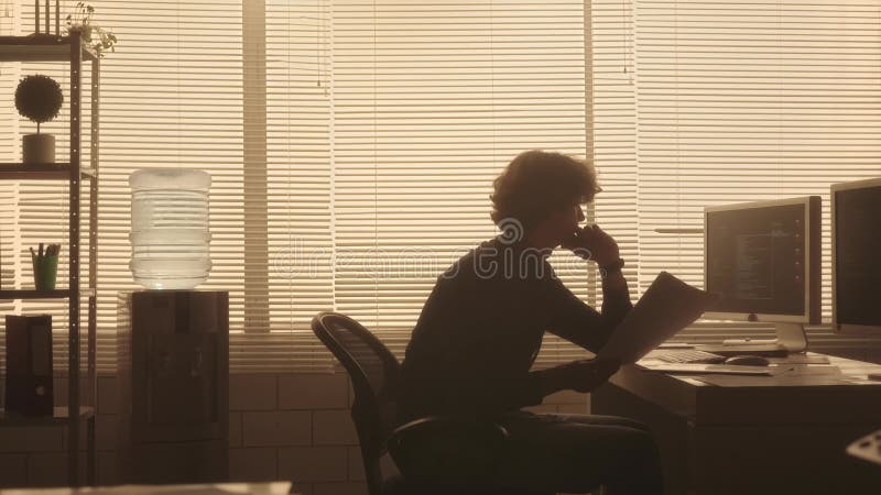The Silhouette of a Young Man is Typing on a Computer Keyboard, Looking ...