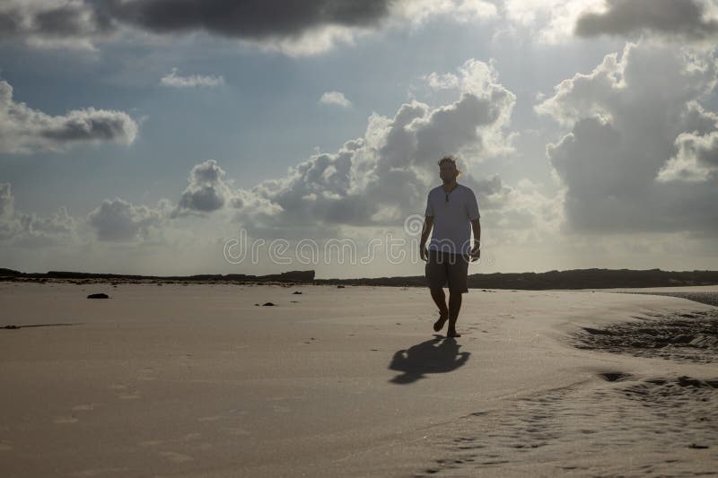 Silhouette of a Young Man Walking on a Lonely Beach Stock Photo - Image ...