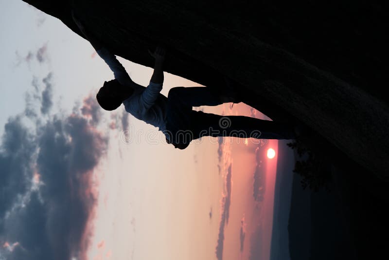 The Silhouette of a Young Strong Man Climbing a Rock Wall at Sunset ...