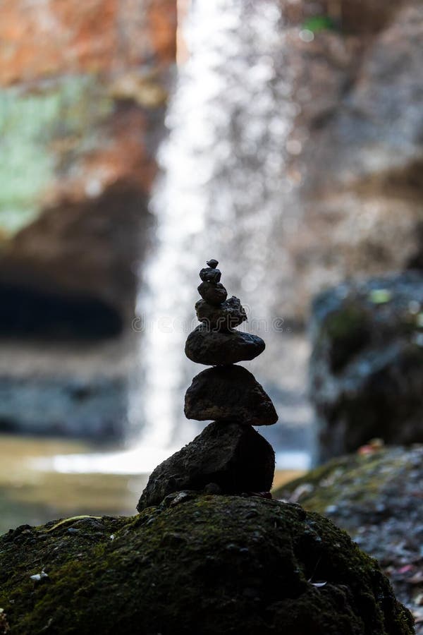 Silhouetted Cairn Stacked Stones with Blurry Background of Waterfall ...