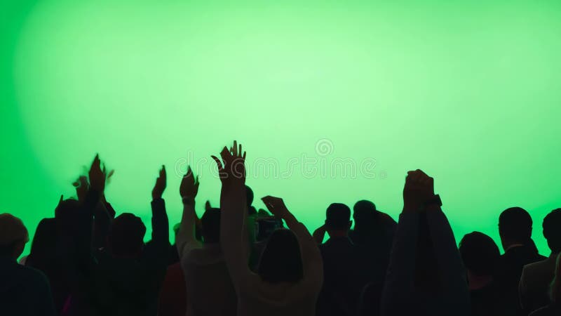 Silhouetted Crowd Cheering and Clapping in Front of a Vibrant Green ...