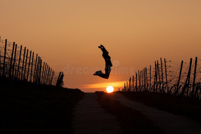 Silhouetted Man Jumping in Sunset Stock Photo - Image of clouds ...