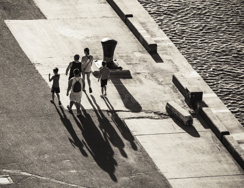 Silhouettes of a Group of People Casting Long Shadows on an Asphalt ...