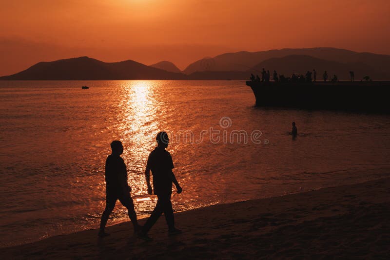 Silhouettes of People Strolling Along the Seashore at Dawn. Stock Image ...