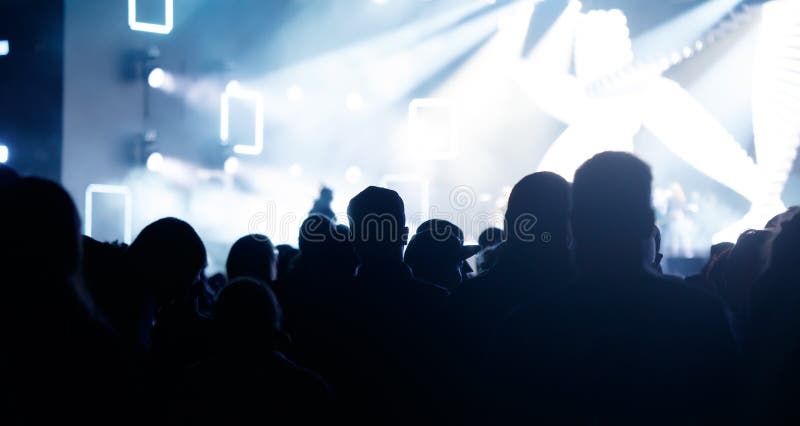 Silhouettes of Spectators Against a Background of Blue Light at a ...