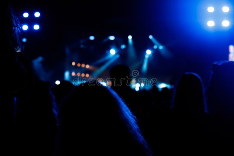 Silhouettes of Spectators Against a Background of Blue Light at a ...