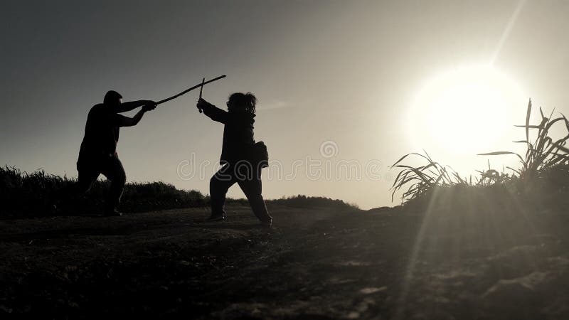Silhouettes of Two Samurai Fighting with Swords in the Rays of Sunset ...