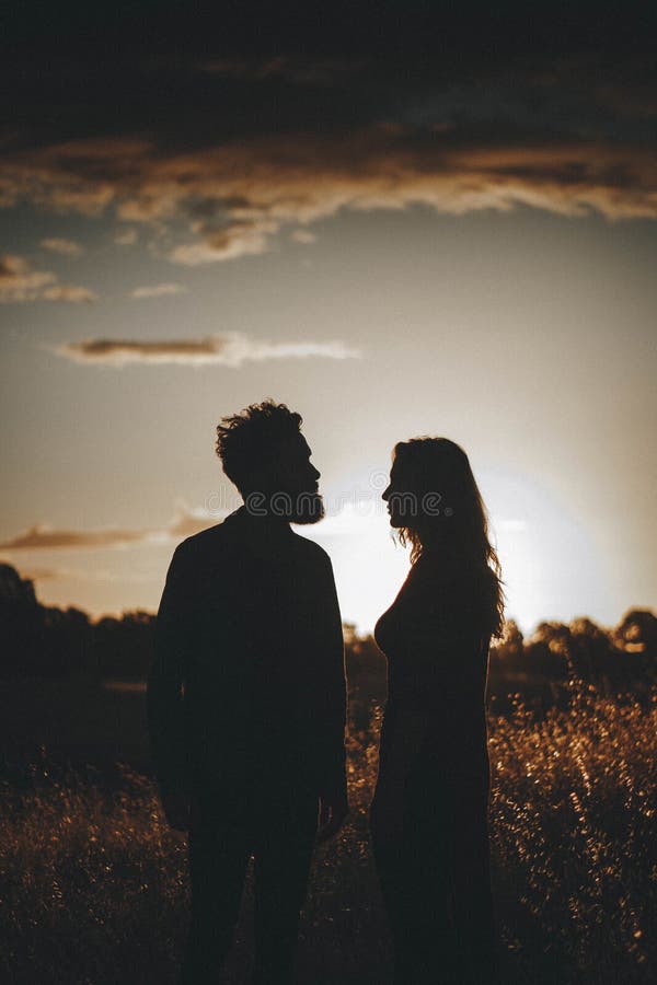 Silhouettes of Young Couple Standing in a Field during Sunset Stock ...