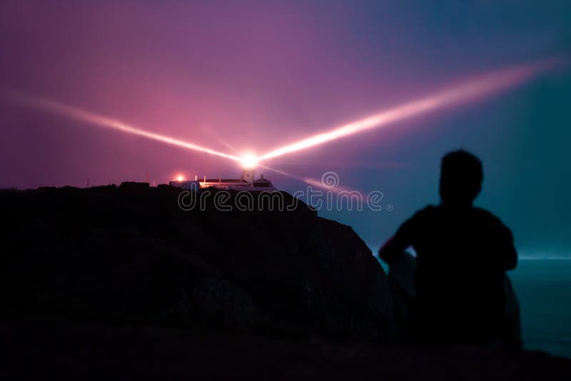 Silouette of a Young Man Watching the Beam of a Light House in the Dark ...