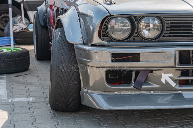 A Silver BMW E30 with a Black Stripe, Stationed at an Angle on a Brick ...