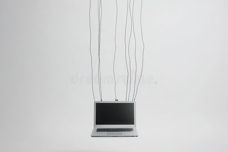A Silver Laptop Suspended by Black Wires Against a White Background ...