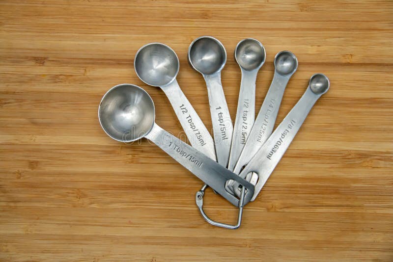 Silver Measuring Spoons on a Wooden Cutting Board Stock Image - Image ...