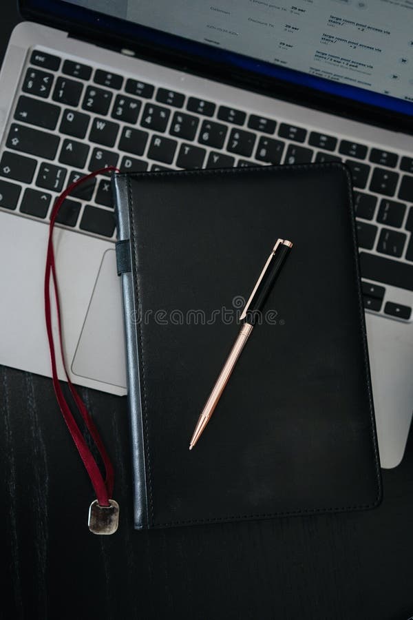 A Silver Pen and a Black Notepad Lie on the Laptop Stock Photo - Image ...