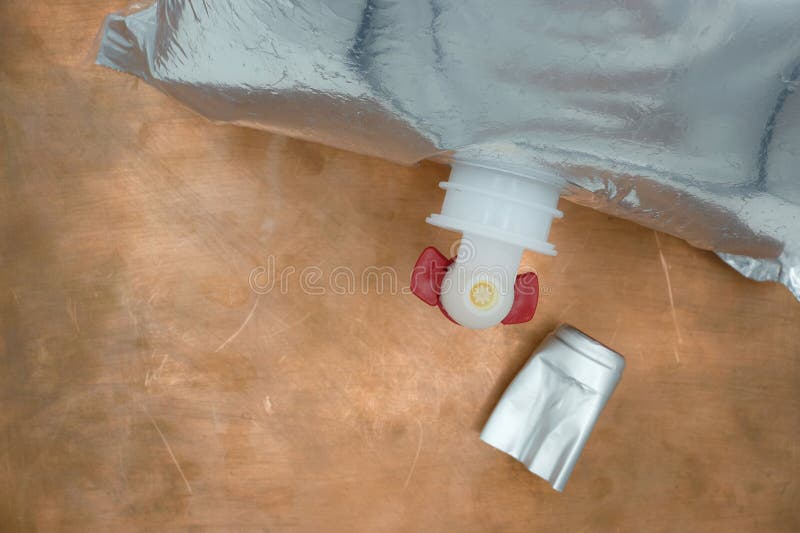Silver Plastic Wine Bag in Box and Wine Bottle Foil Cap on a Copper ...