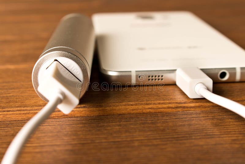 Silver Power Bank Charging Smartphone on Wooden Table Stock Image ...