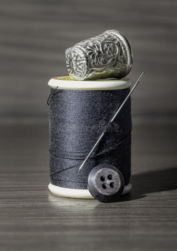 Silver Sewing Needle Stuck in a Spool of Black Thread with Silver ...