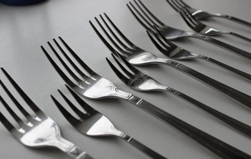 Silvery Forks of Different Sizes in Line on a Clean White Table Stock ...