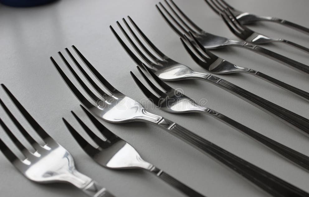 Silvery Forks of Different Sizes in Line on a Clean White Table Stock ...